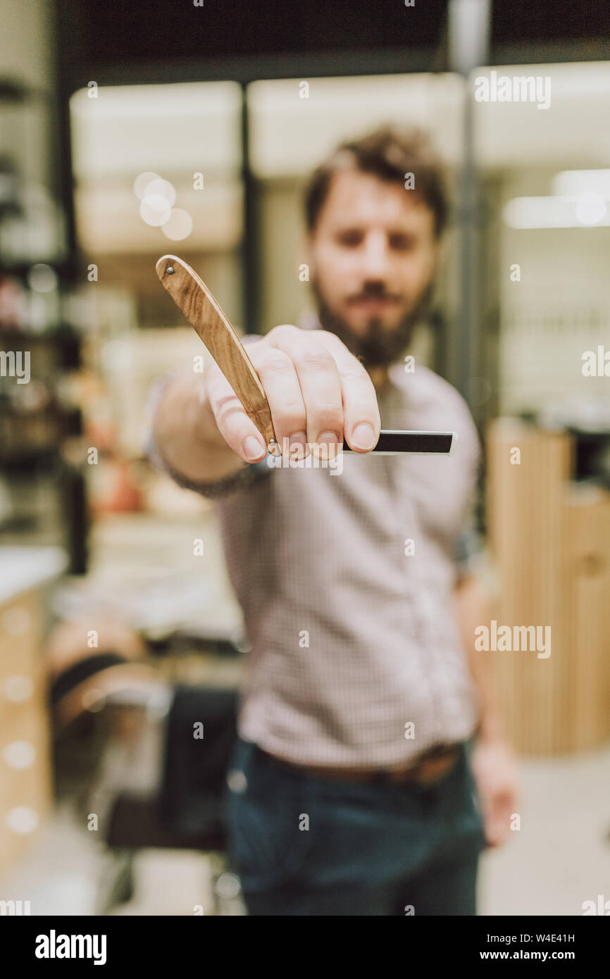 Modern barber holding razor at barbershop Stock Photo - Alamy