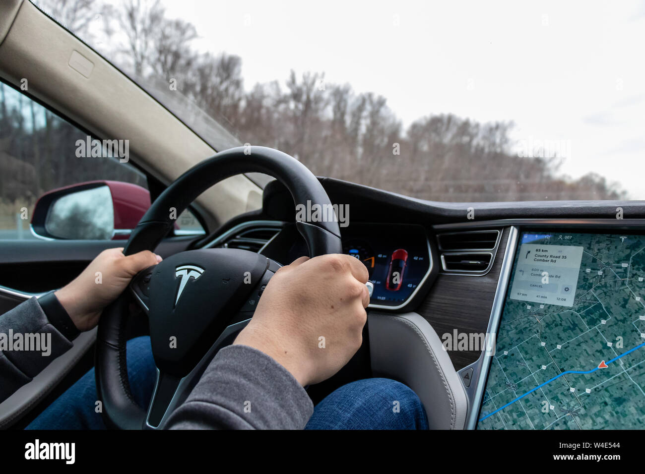 Man behind the wheel of a Tesla Model S, as he drives down the highway ...
