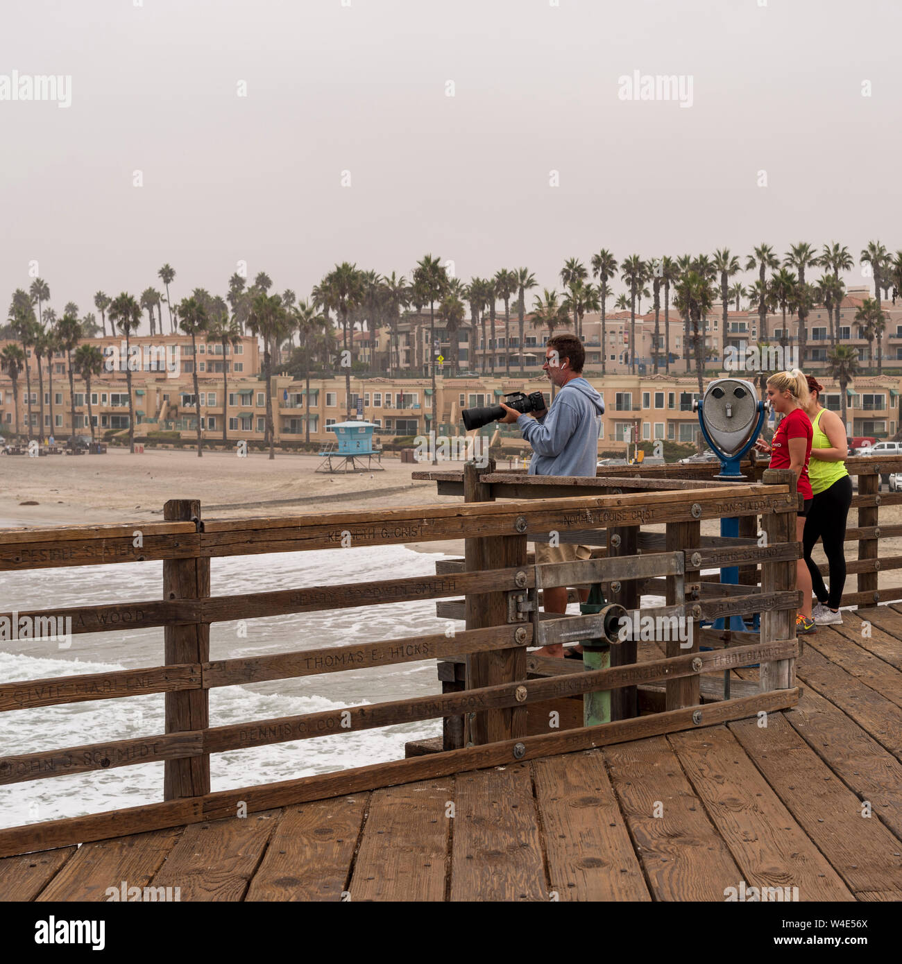 People watching surfing event below, photographer with large lens on ...