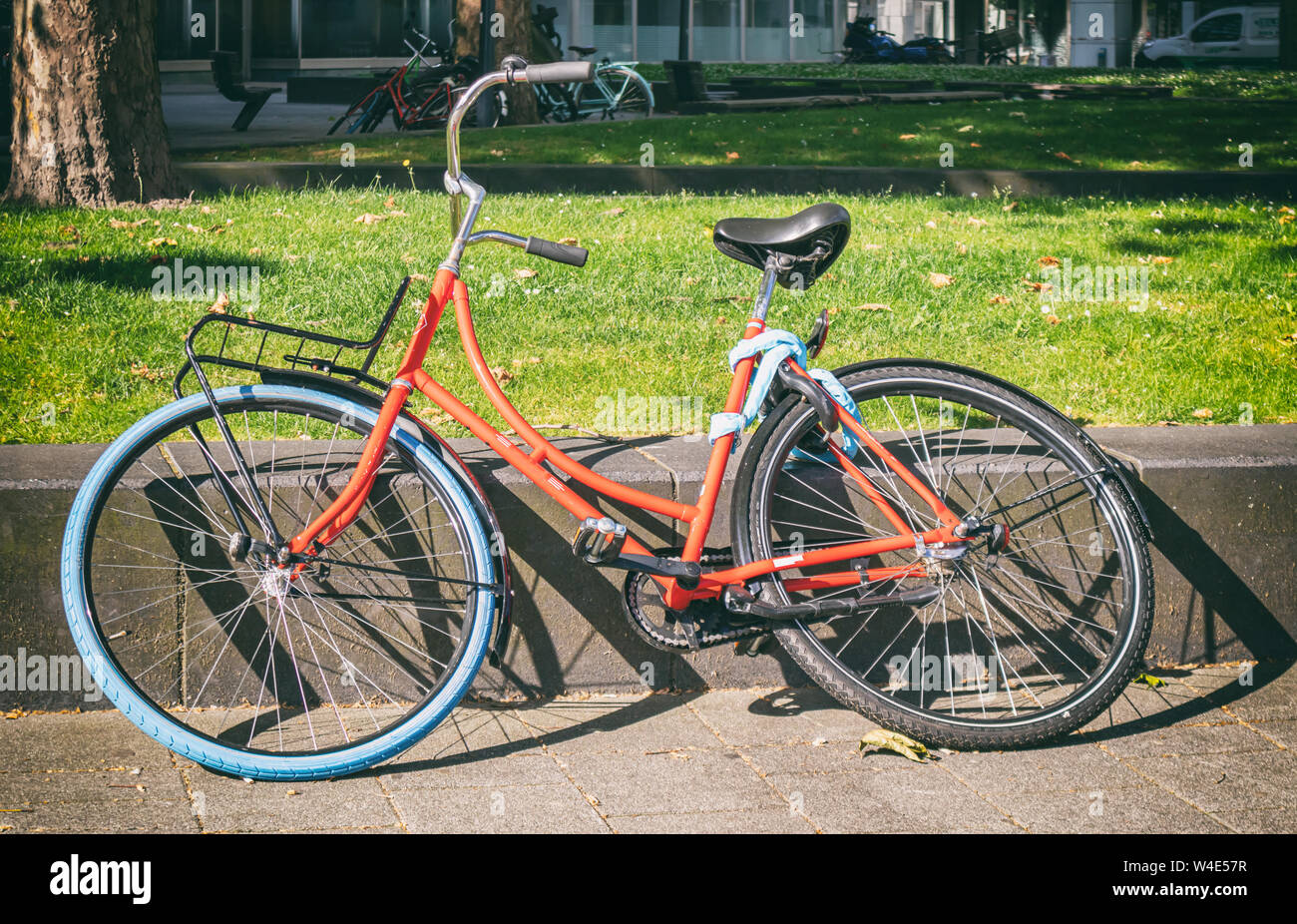 Orange color bicycle. Bike unlocked leaned on a sidewalk wall in ...