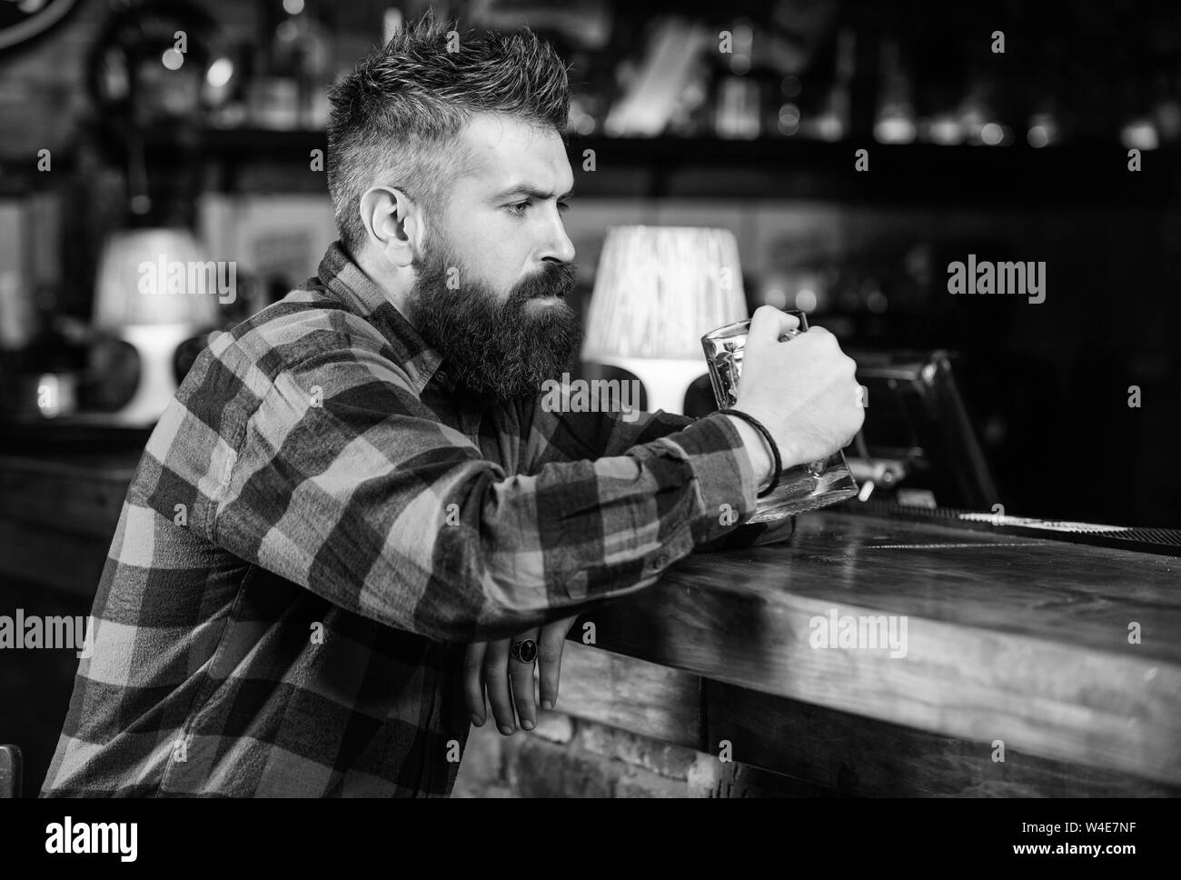 Man with beard spend leisure in dark bar. Hipster relaxing at bar with ...