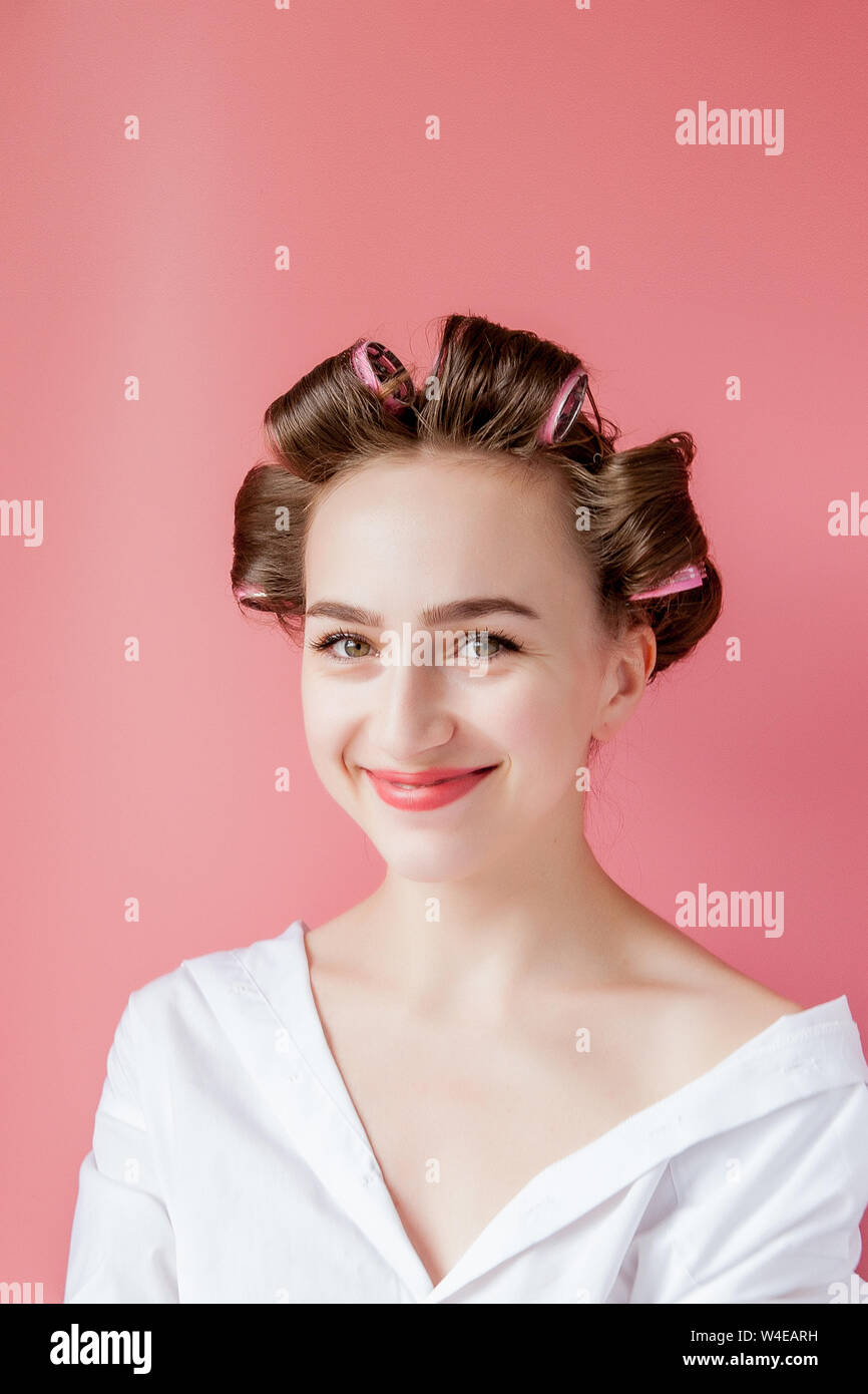 Beautiful girl in hair curlers on pink background Stock Photo - Alamy