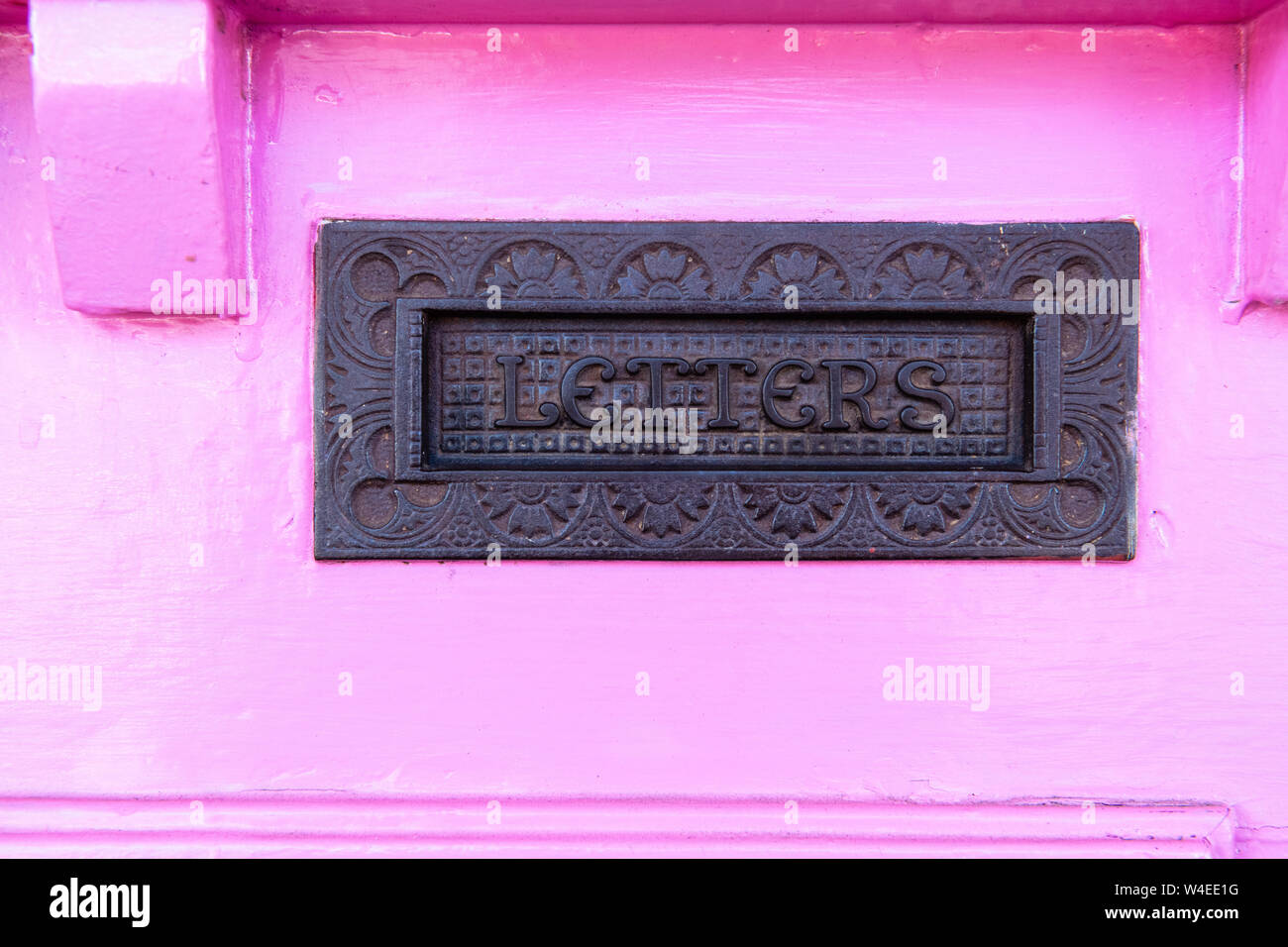 Letter box in a roughly painted rustic pink door - super close up Stock ...