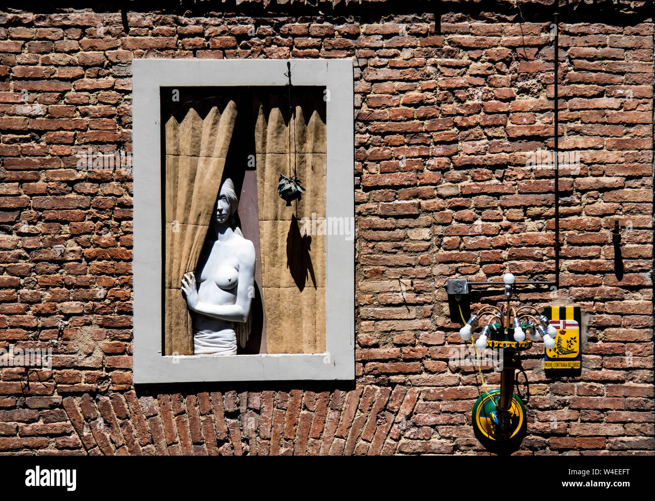 Statue of woman peeking from behind a curtain in a fake window frame in ...