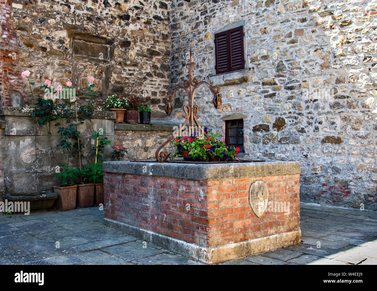 Brick garden centerpiece with flowers in the middle of a stone ...