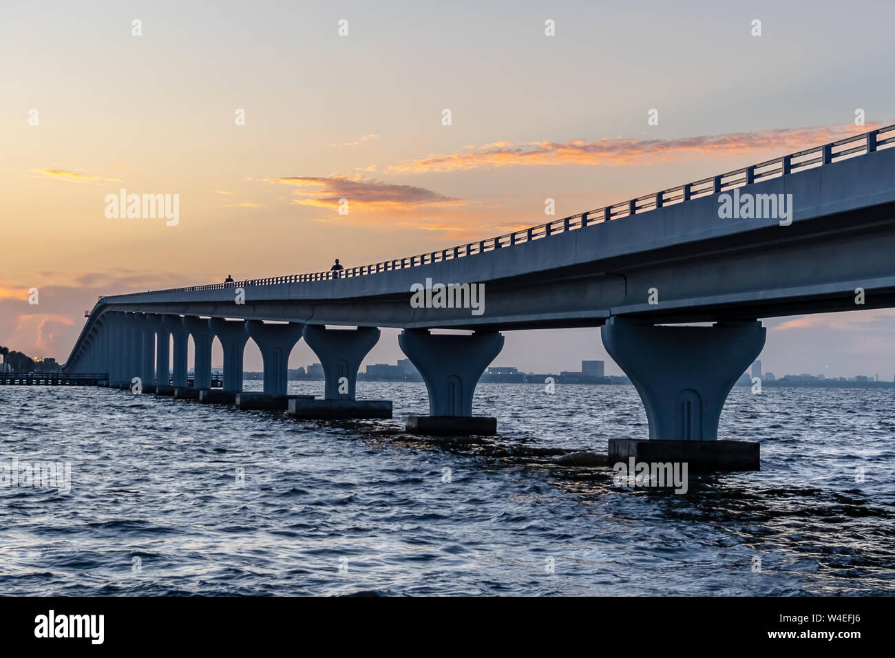 Early morning, as the sun is rising, a long runner is a silhouette on a ...