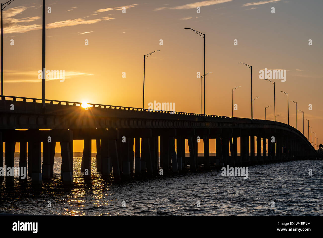 View of the sun rising over a silhouette of a bridge in Florida, USA ...