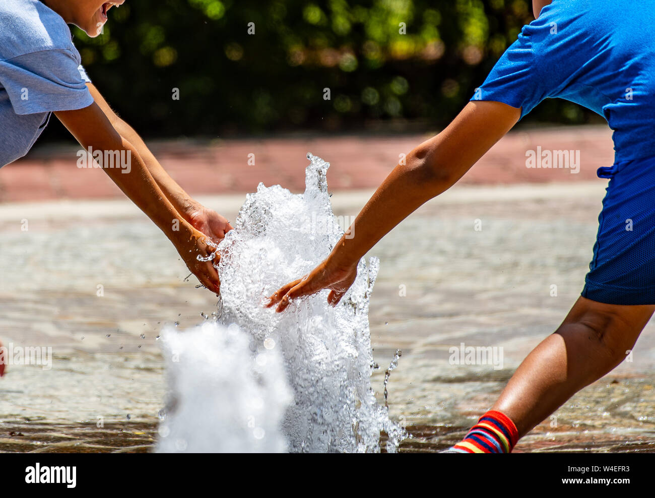 Kids having fun playing water games sticking their hands in the park's ...