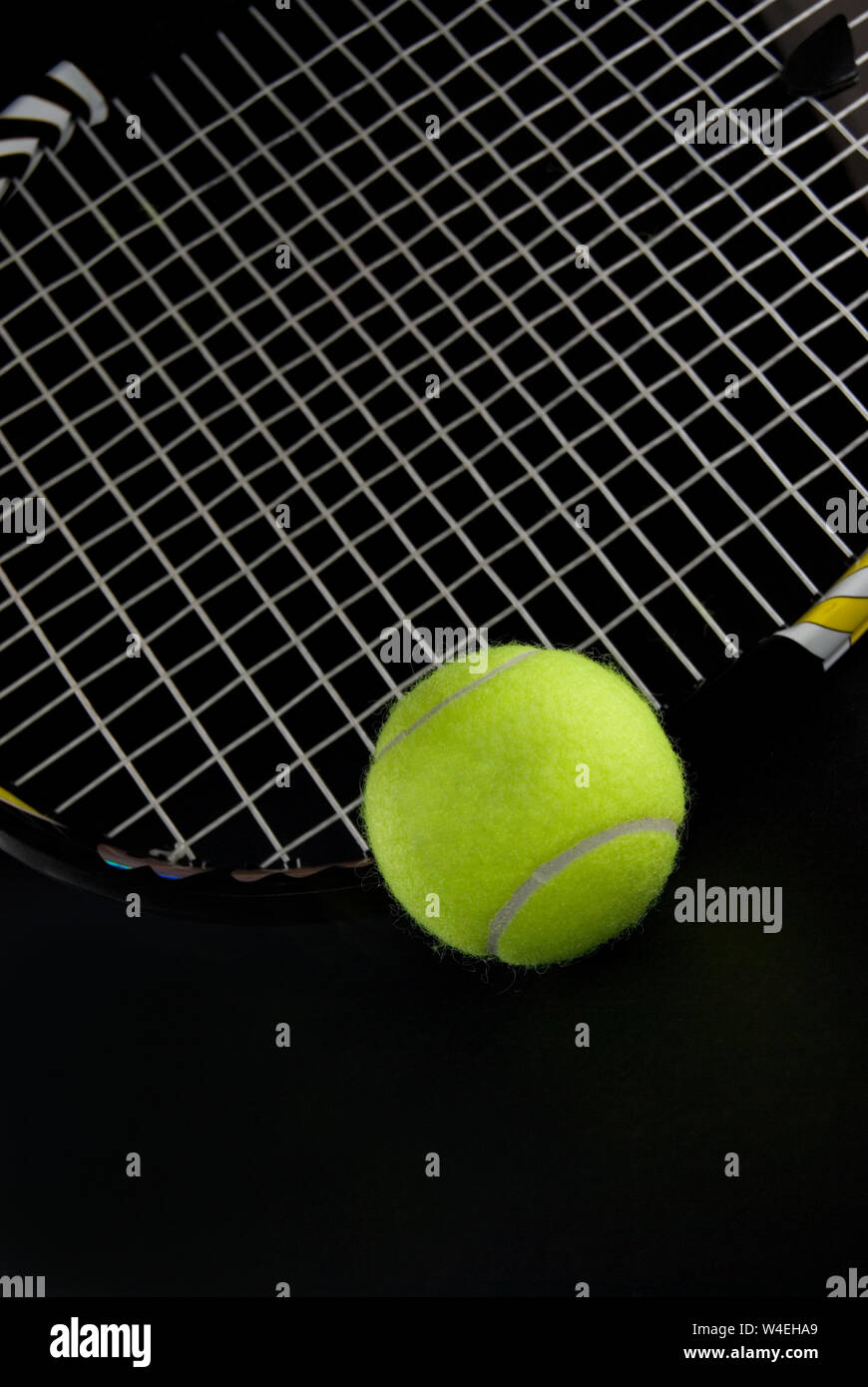 Green Tennis Ball and Black Racquet on Dark Background Stock Photo - Alamy