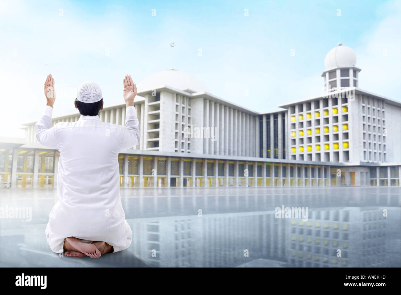 Rear View of Asian Muslim man sitting in pray position while raised ...