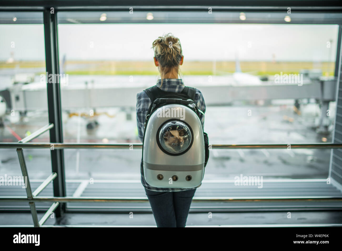 Woman wearing a space shuttle cat carrier on her back while waiting for ...