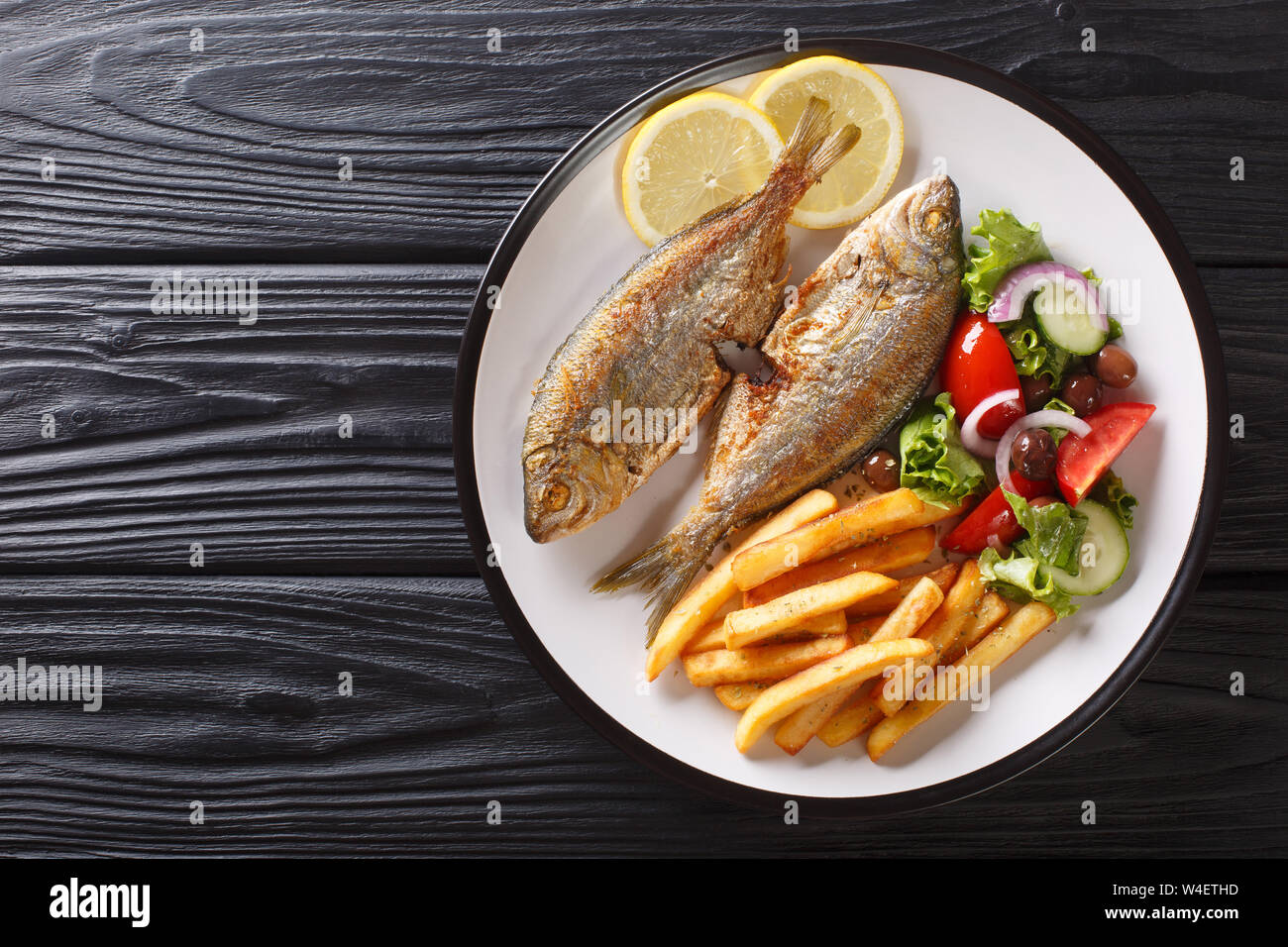 Traditional fried Sarpa salpa fish with lemon and side dish of fresh ...