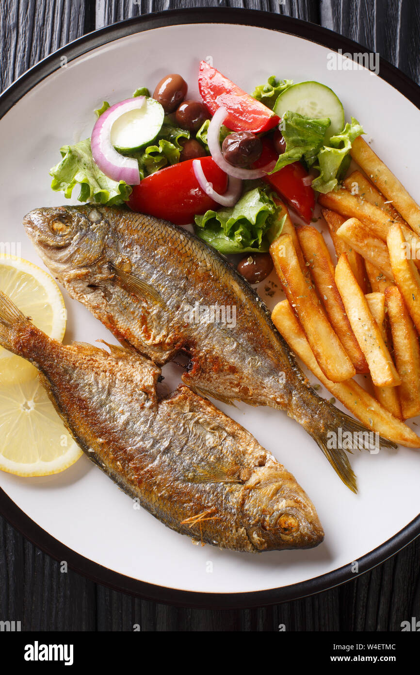 Fried Salema porgy fish with a side dish of fresh salad and french ...