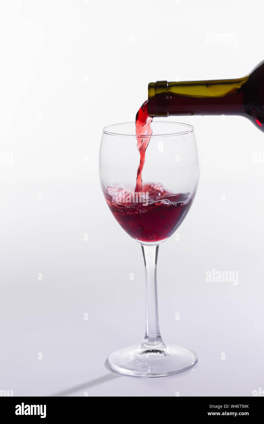 Red wine bottle pour glass on white background Stock Photo - Alamy
