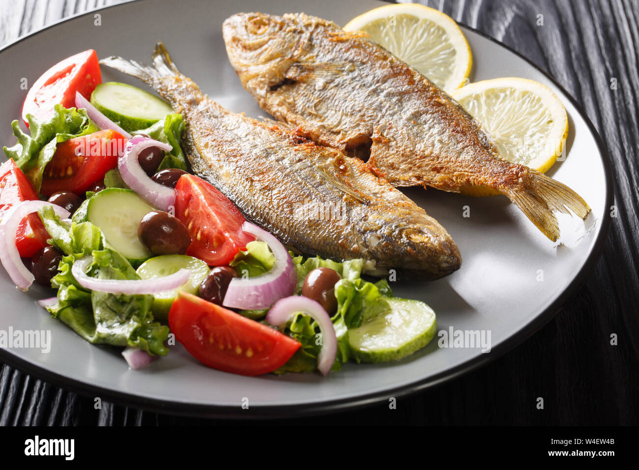 Spicy fried Salema porgy sea fish with lemon and fresh vegetable salad ...
