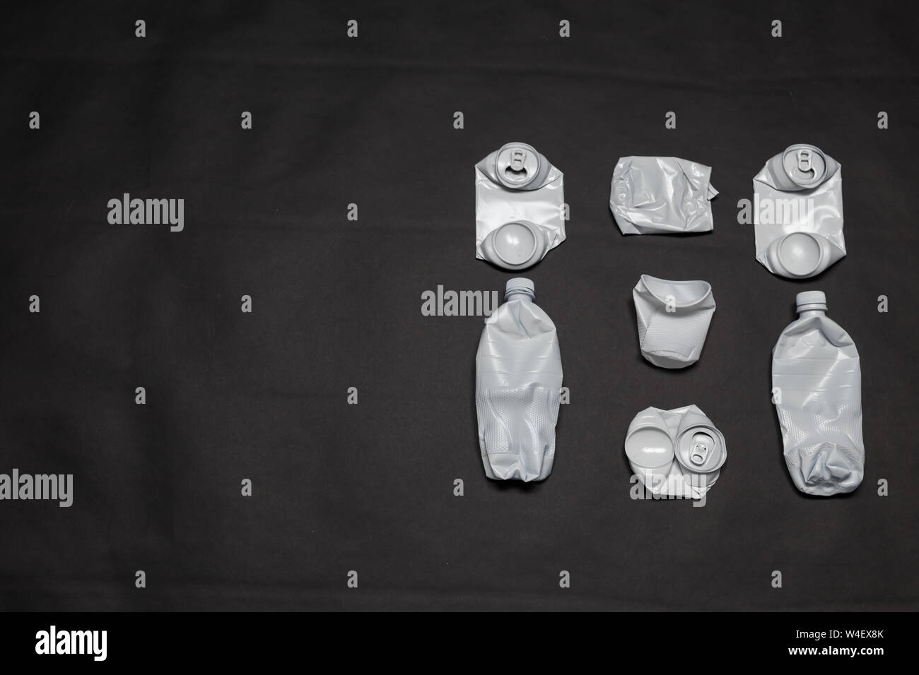Crumpled plastic and metal cans lie on a black background with copy ...