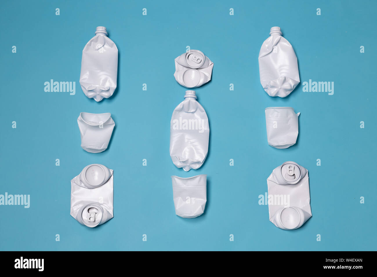 Crumpled plastic and metal cans lie on a blue background. Concept of ...
