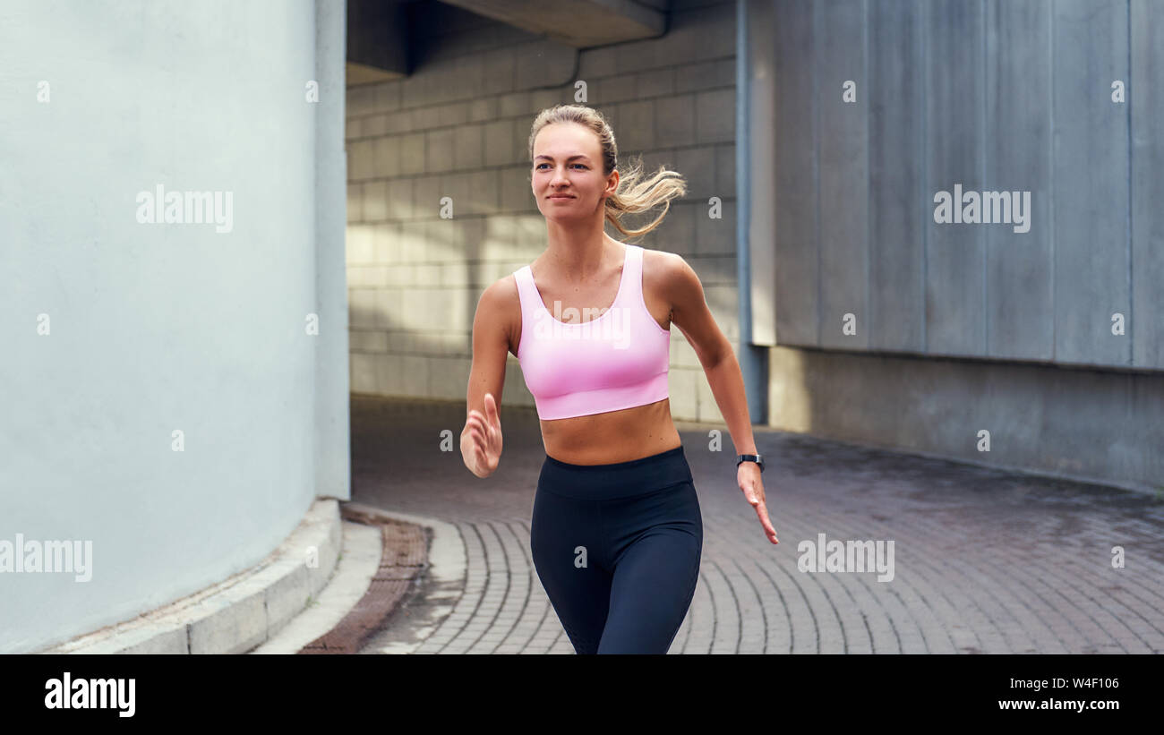Enjoying run. Young smiling woman in comfortable sports clothing is ...