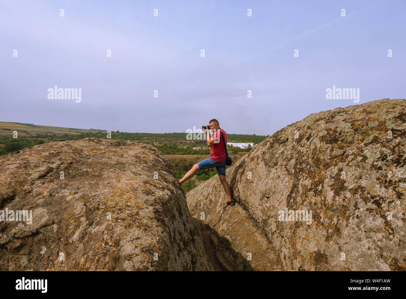 The photographer takes pictures of nature, standing on top of a cliff ...