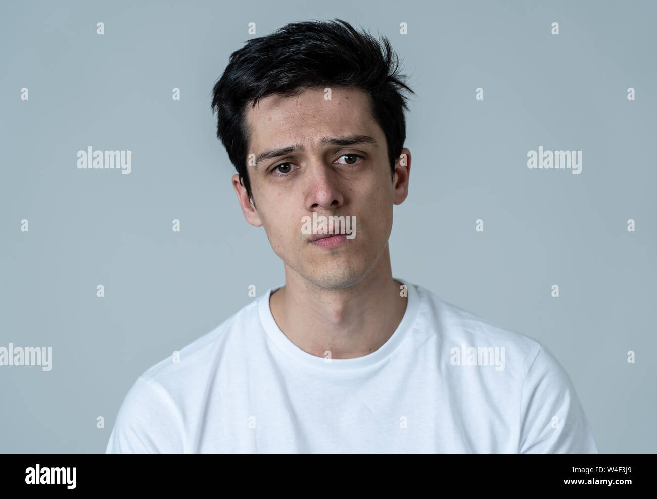 Close up of a young sad man, serious and concerned, looking worried and ...