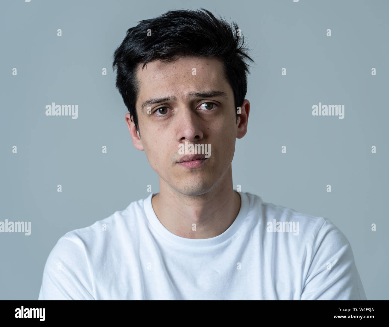Close up of a young sad man, serious and concerned, looking worried and ...