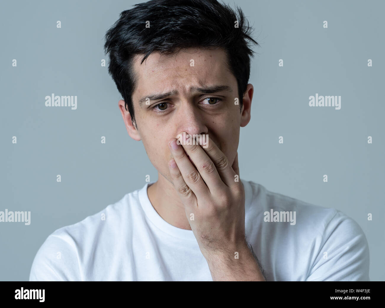 Close up of a young sad man, serious and concerned, looking worried and ...