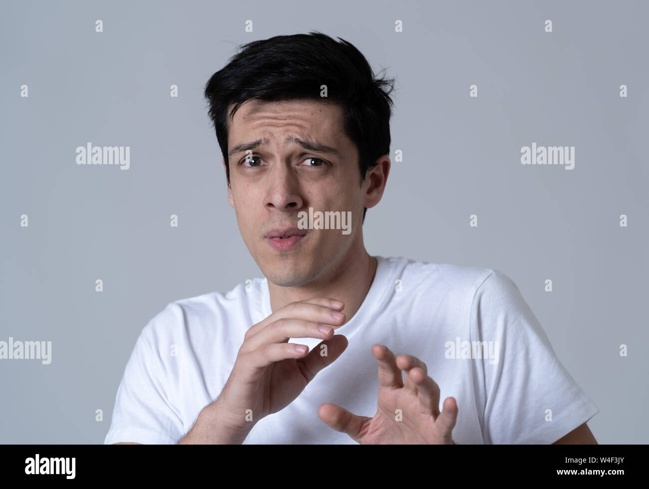 Young man feeling scared and shocked making fear, anxiety gestures ...
