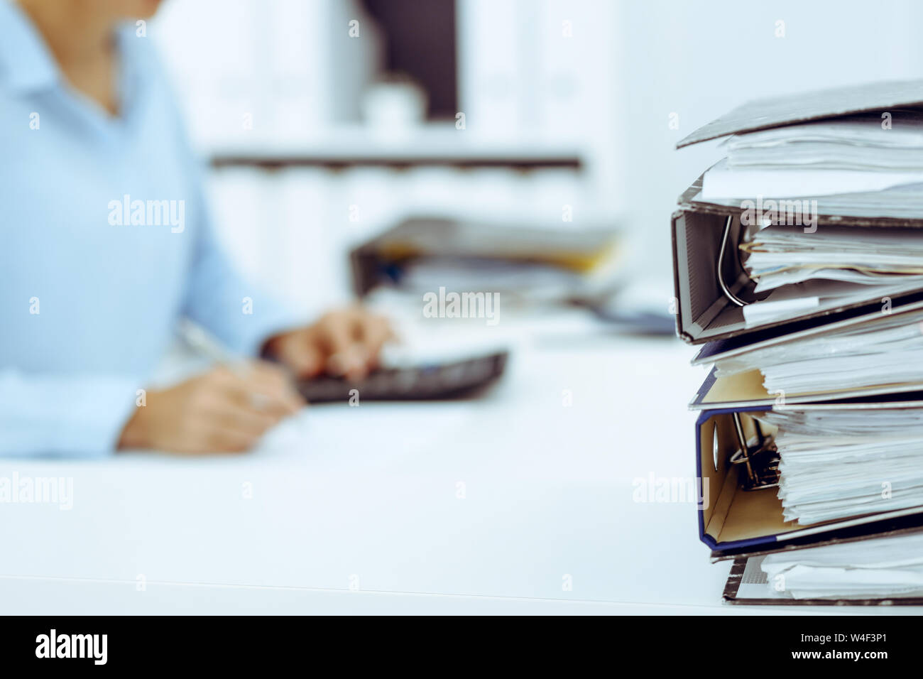 Binders with papers are waiting to be processed by business woman or ...