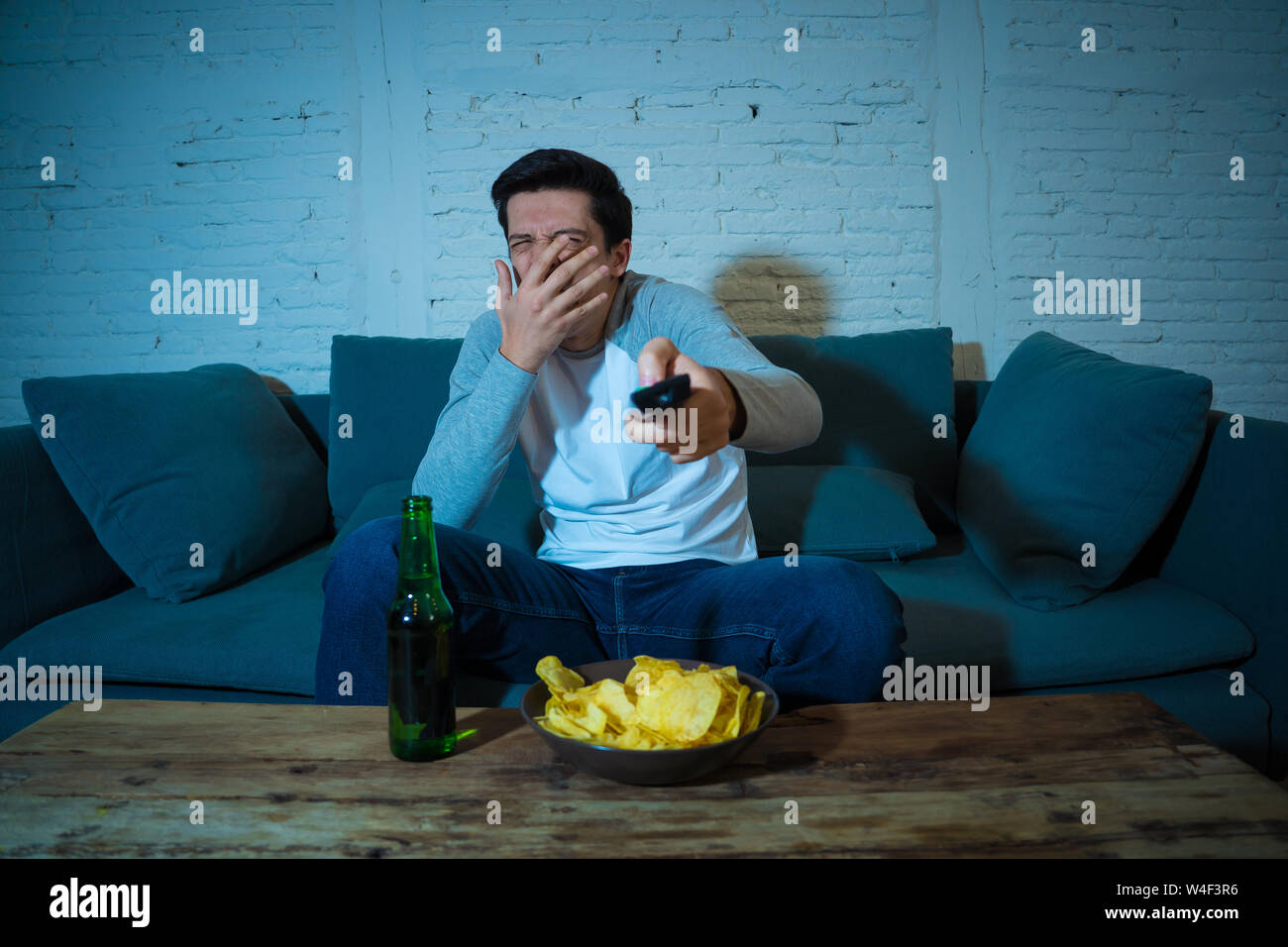 Lifestyle portrait of young scared man watching horror movie or ...