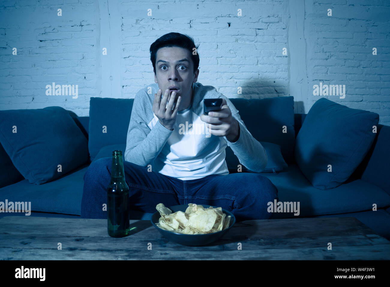 Lifestyle portrait of young scared man watching horror movie or ...