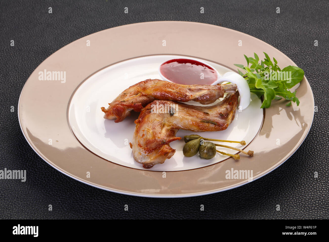 Roasted rabbit legs with cowberry sauce Stock Photo - Alamy