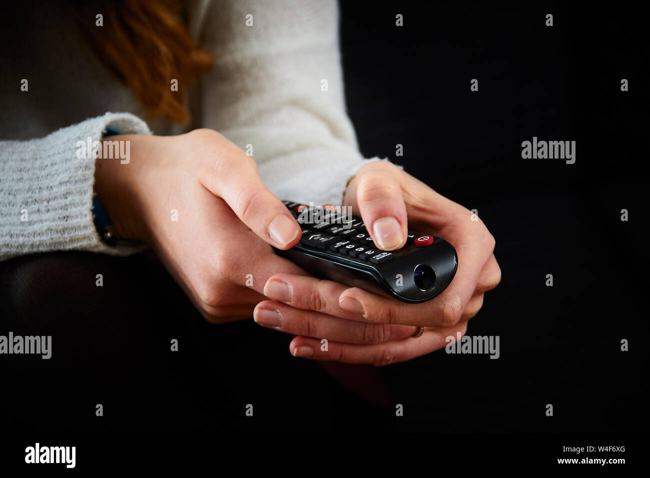 Close-up image of two female hands with remote control pointing forward ...