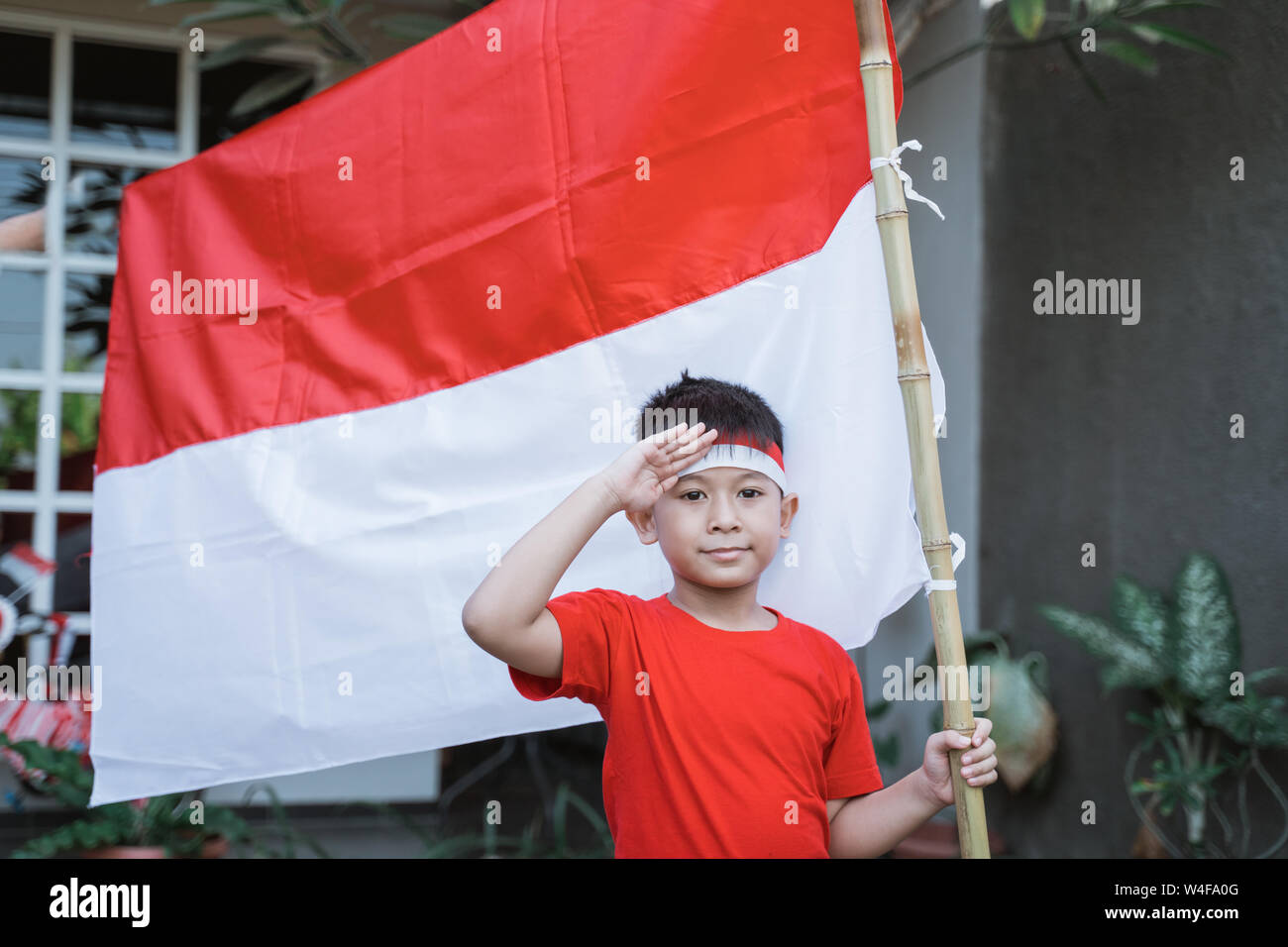 asian kid saluting while holding indonesia flag Stock Photo - Alamy