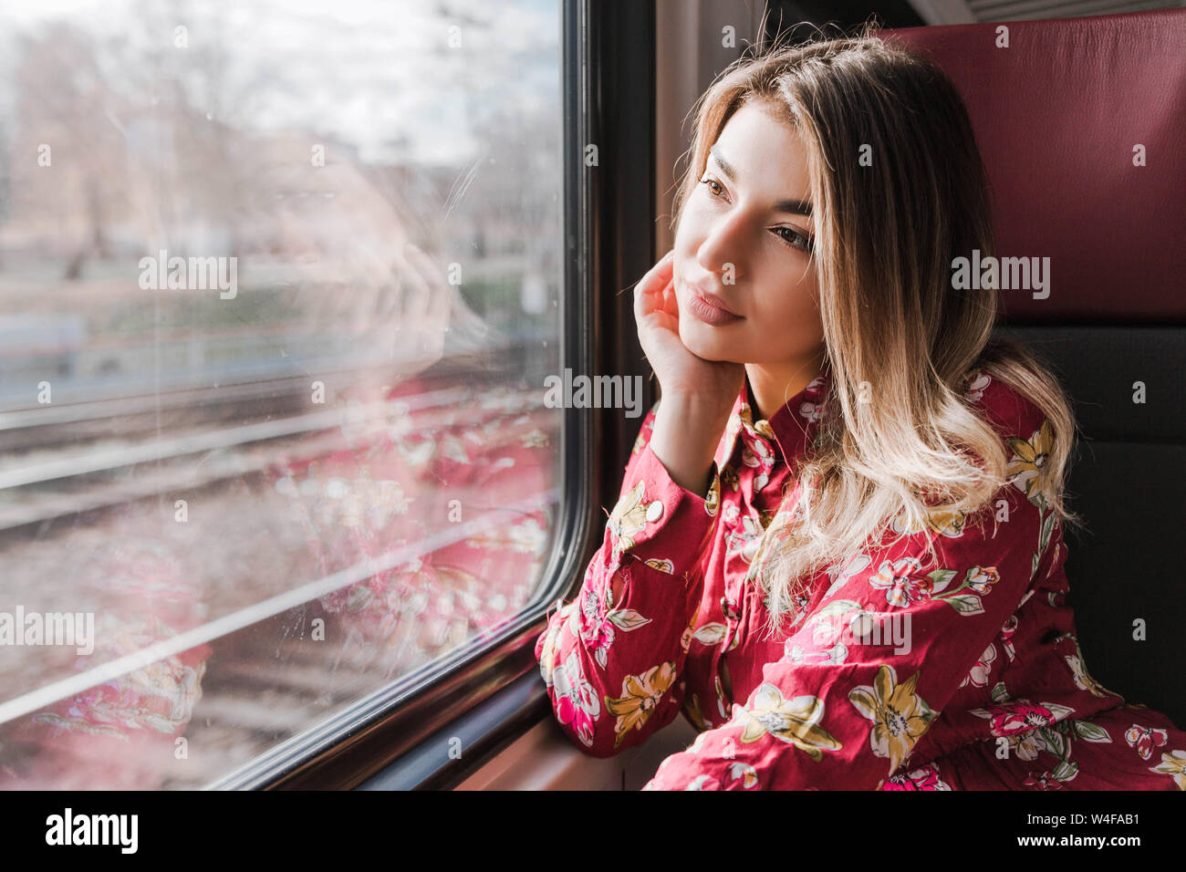 photo of Beautiful girl sitting alone in a train and sadly looks out ...