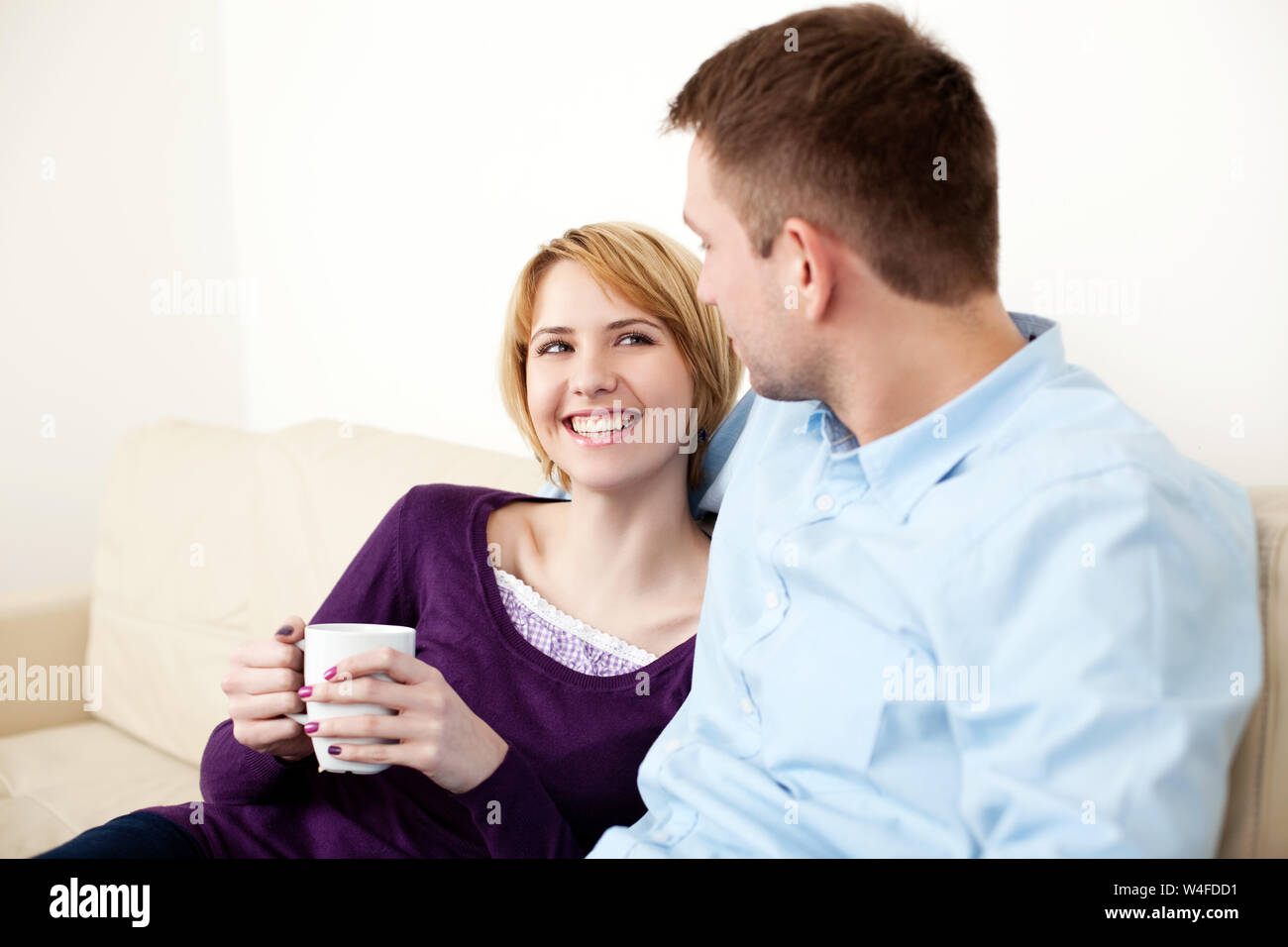 Happy couple sitting together on sofa Stock Photo - Alamy