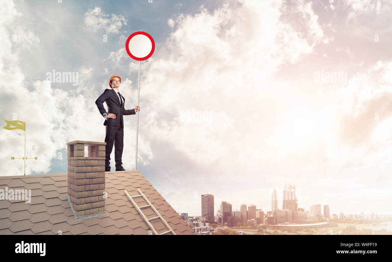 Businessman standing on house roof and holding stop sign. Mixed media ...