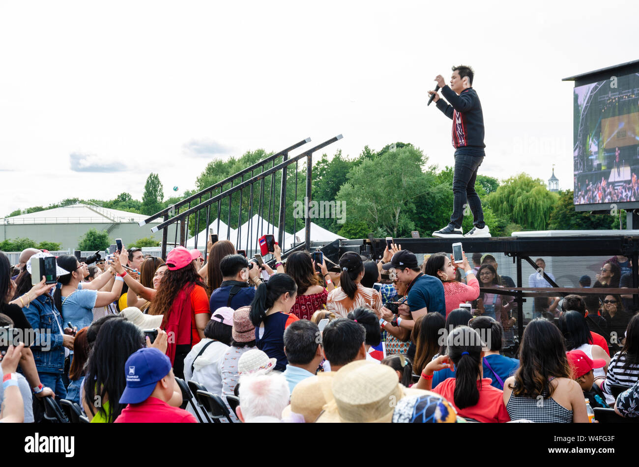 A crowd watches as an artist performs live on stage at a Filipino ...