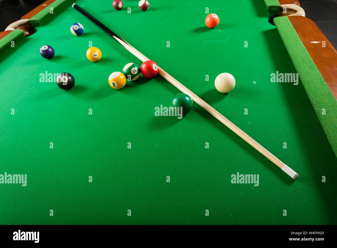 Billiard balls and cue stick on green table. Pool game Stock Photo - Alamy