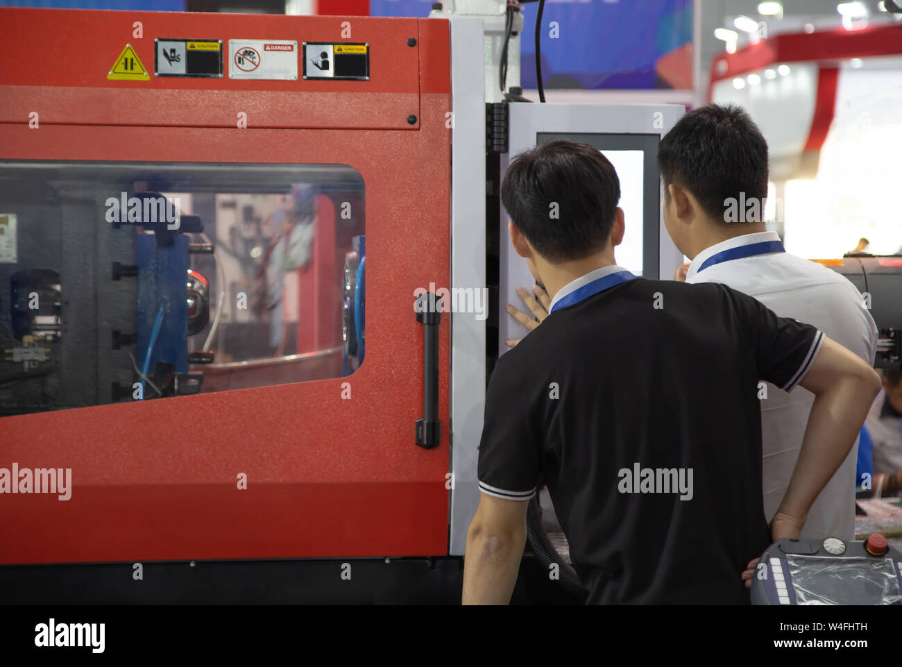 worker operating industrial plastic injection molding press machine for ...