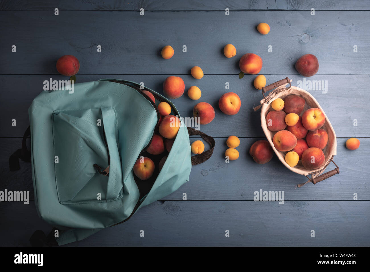 Organic fruits in a school backpack blue table. Ripe peaches and ...