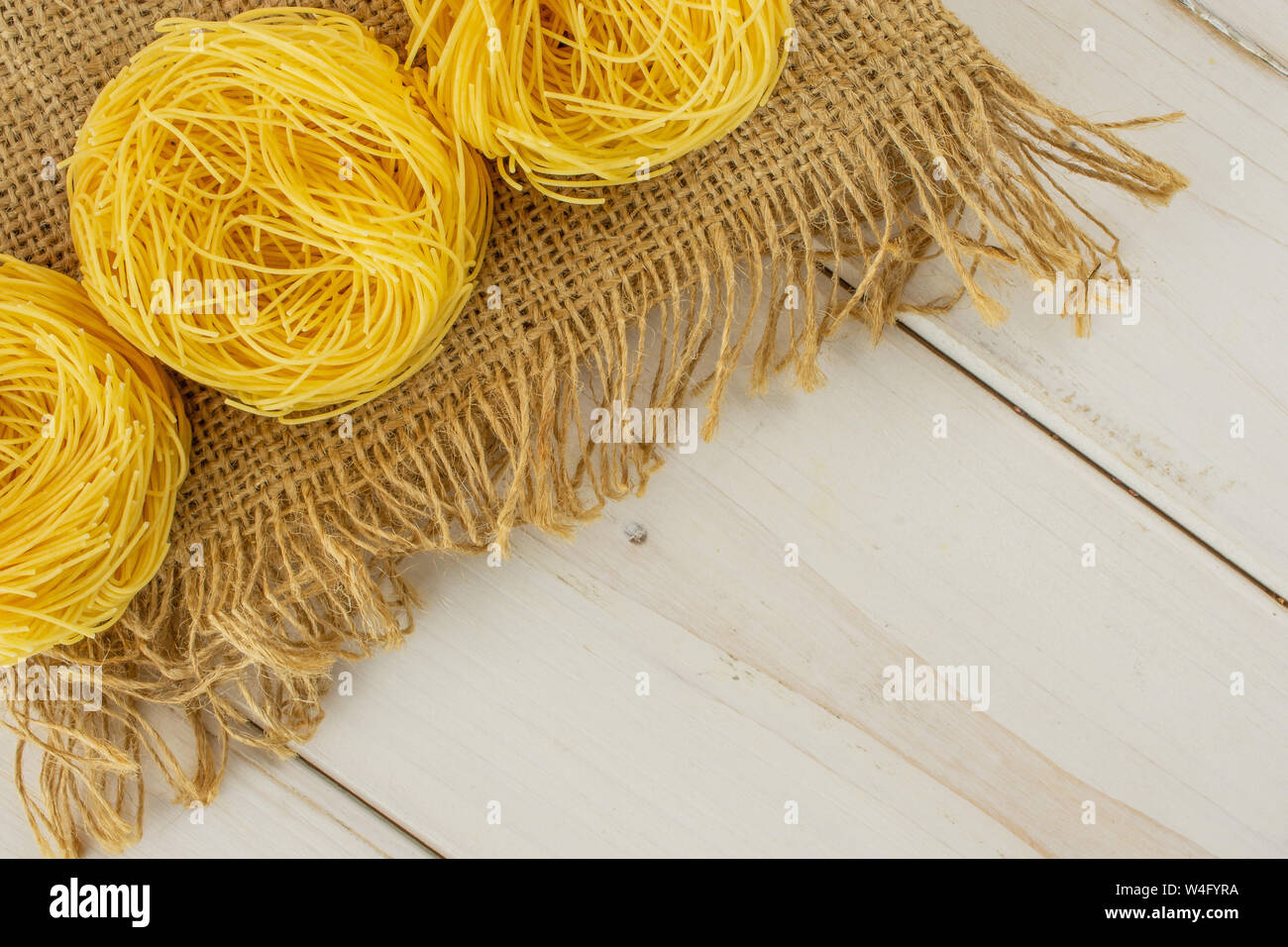 Group of three whole raw pasta angel hair on jute cloth flatlay on ...
