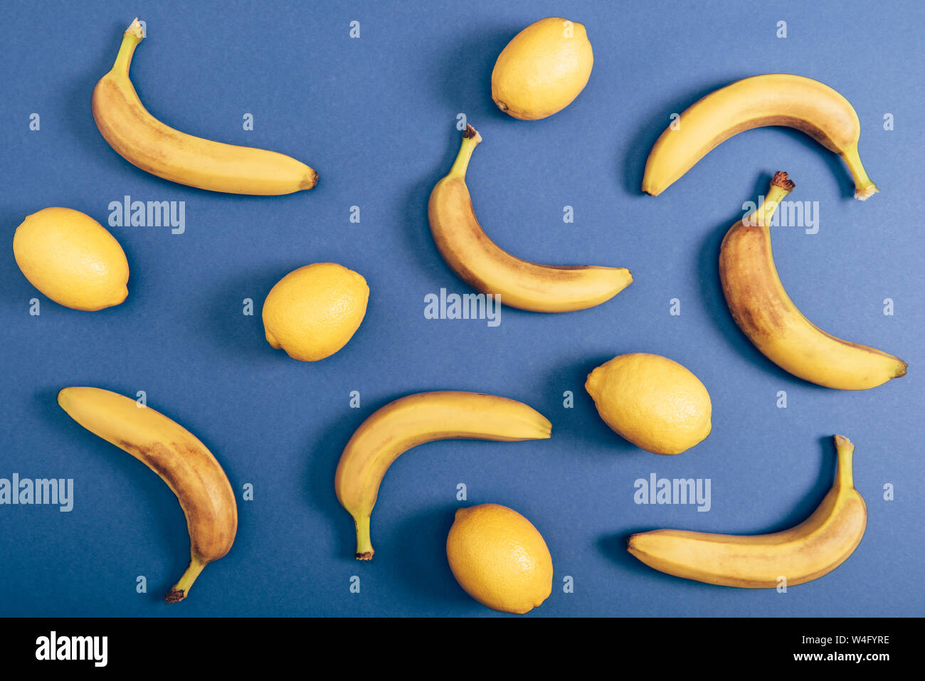Food composition with lemons and ripe bananas lying isolated on blue ...
