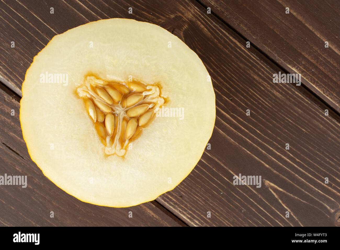 One half of fresh yellow melon canary cross section flatlay on brown ...