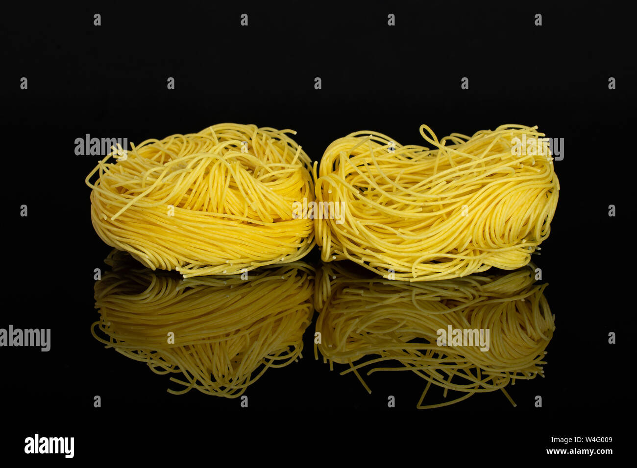 Group of two whole raw pasta angel hair nest shaped isolated on black ...