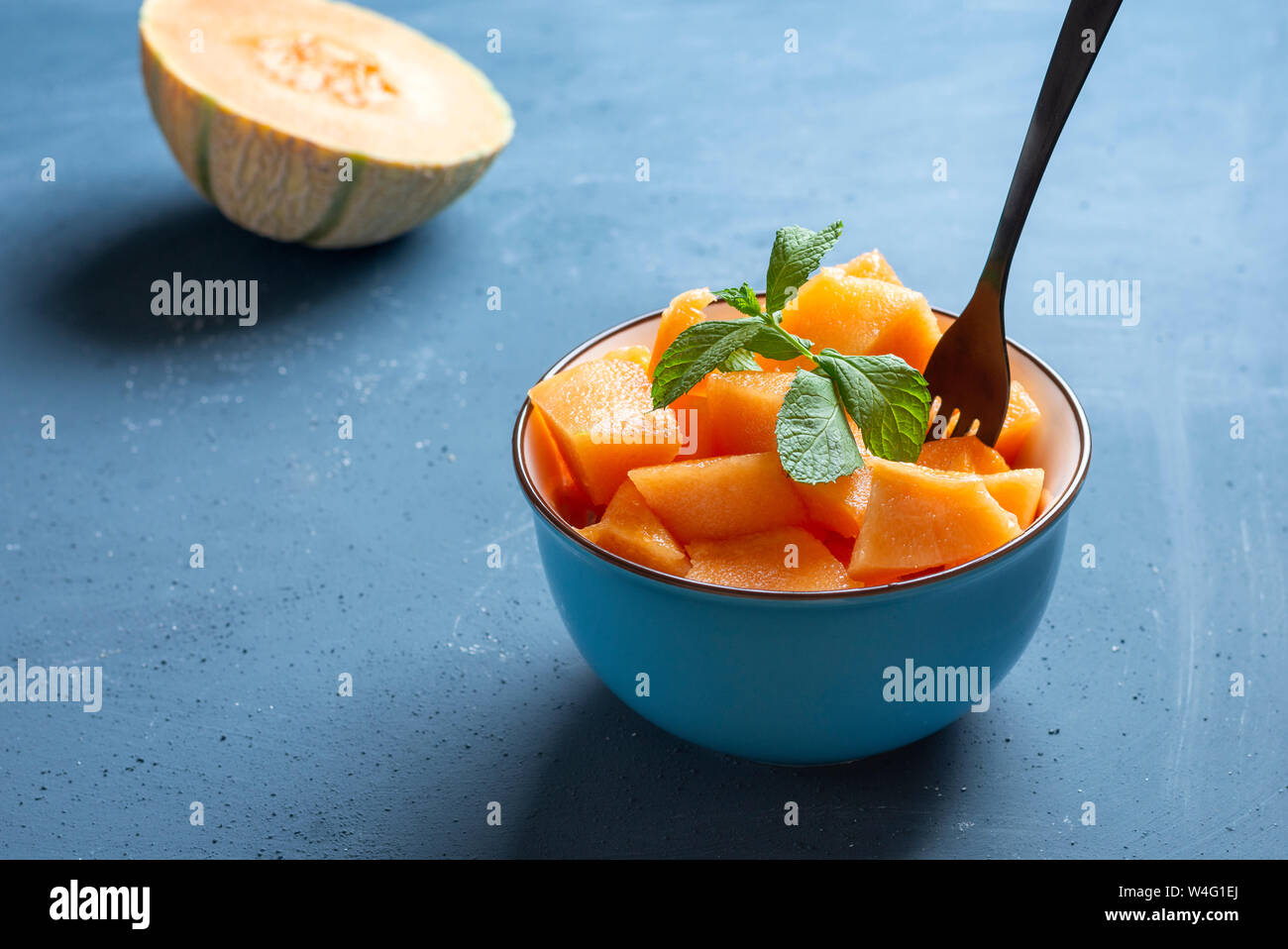 Fresh melon cut into pieces in a bowl and background blue Stock Photo ...