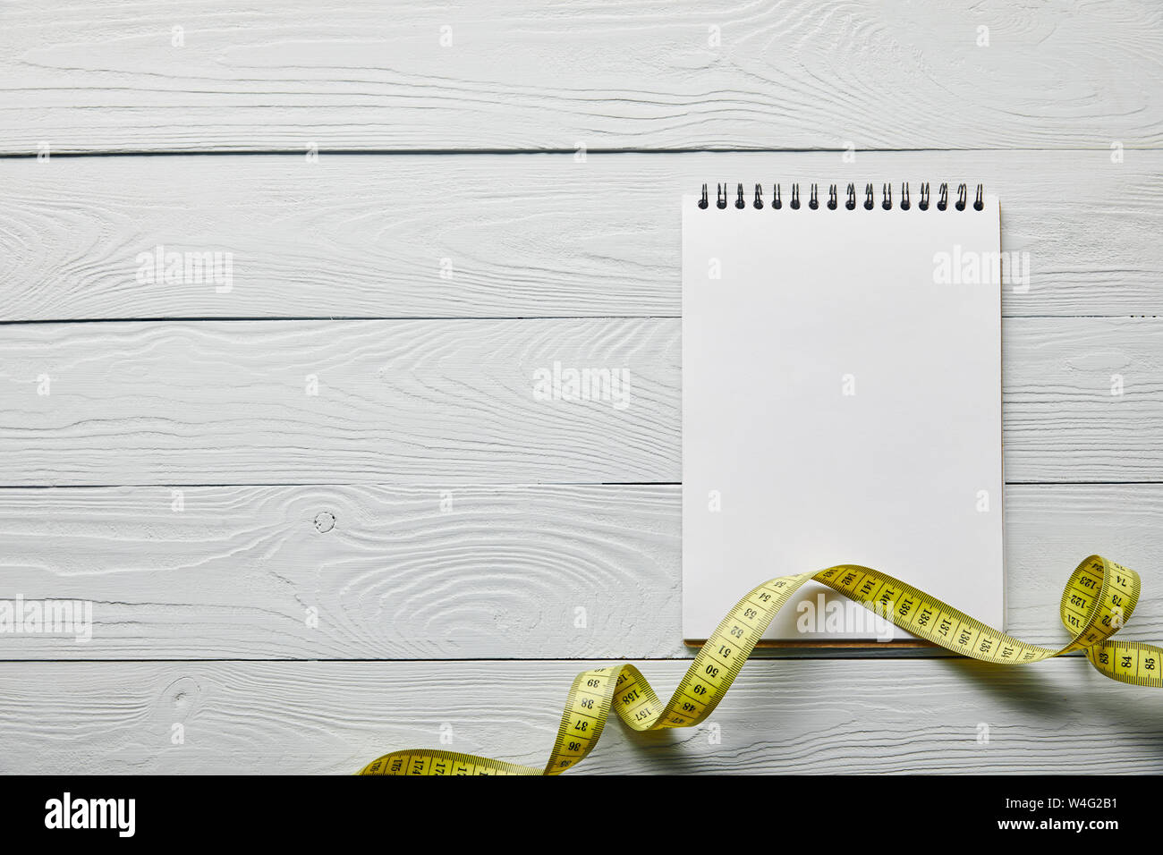 top view of measuring tape and blank notebook with copy space on wooden ...