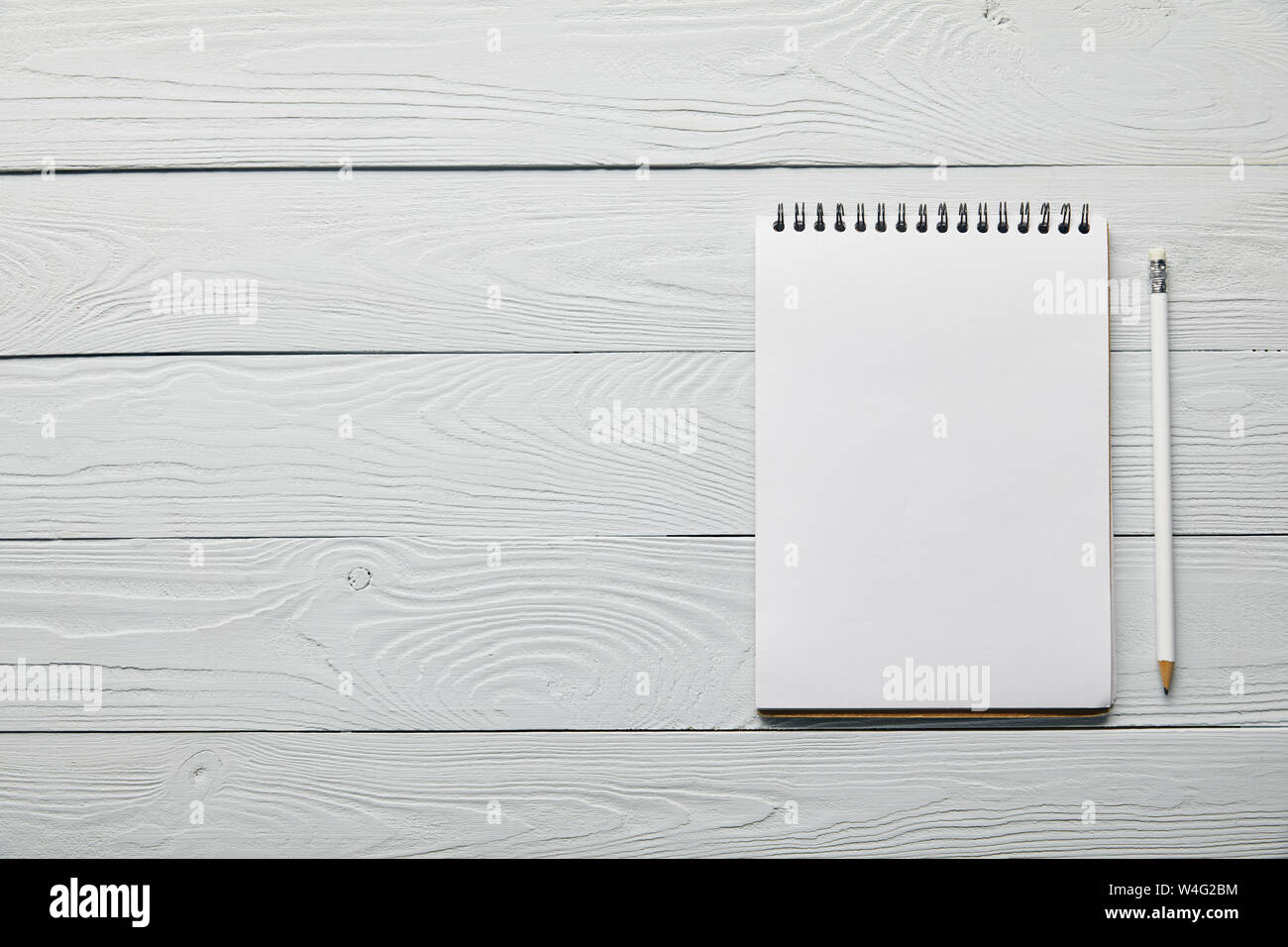 flat lay with blank notebook with copy space and pencil on wooden white ...