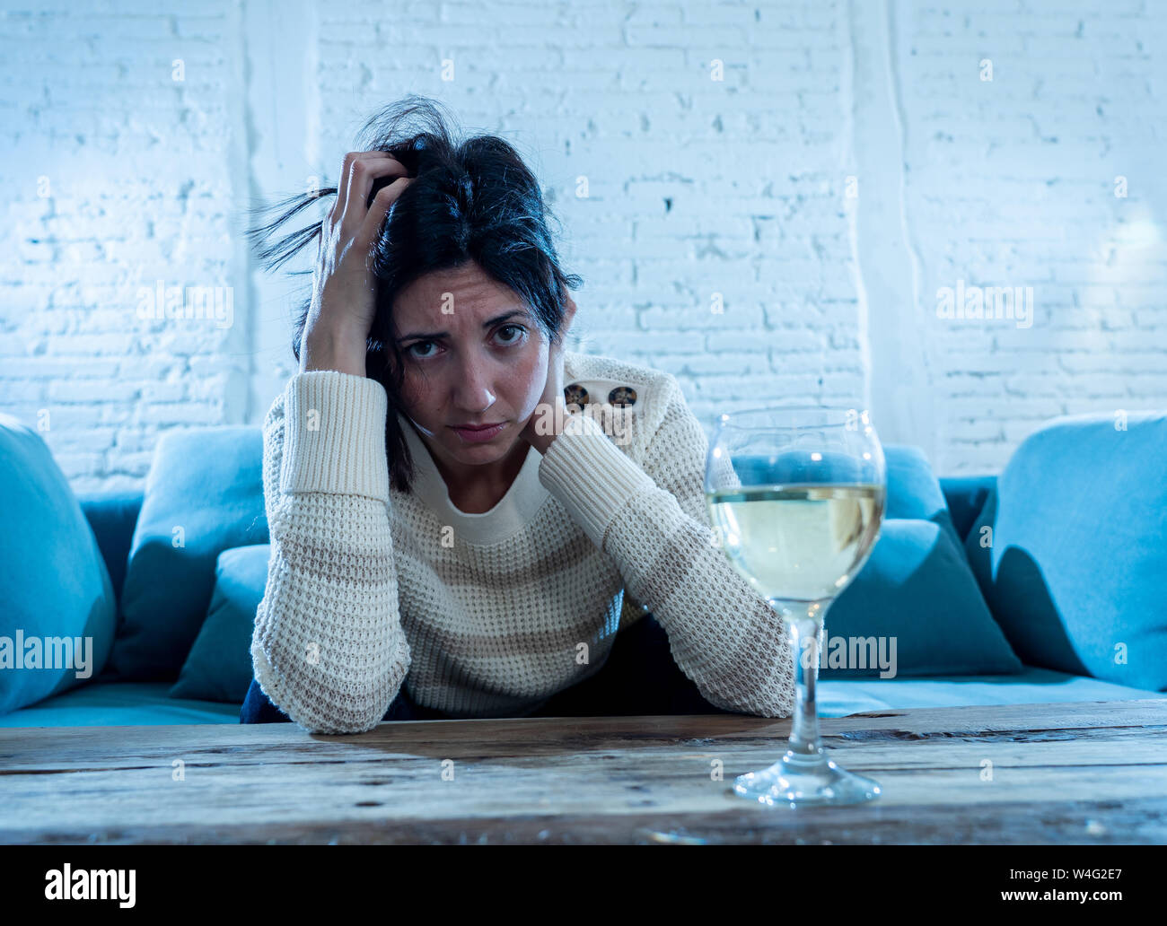 Stressed and hopeless young woman drinking a glass of wine alone at ...