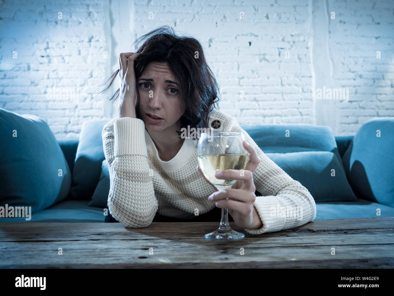 Stressed and hopeless young woman drinking a glass of wine alone at ...