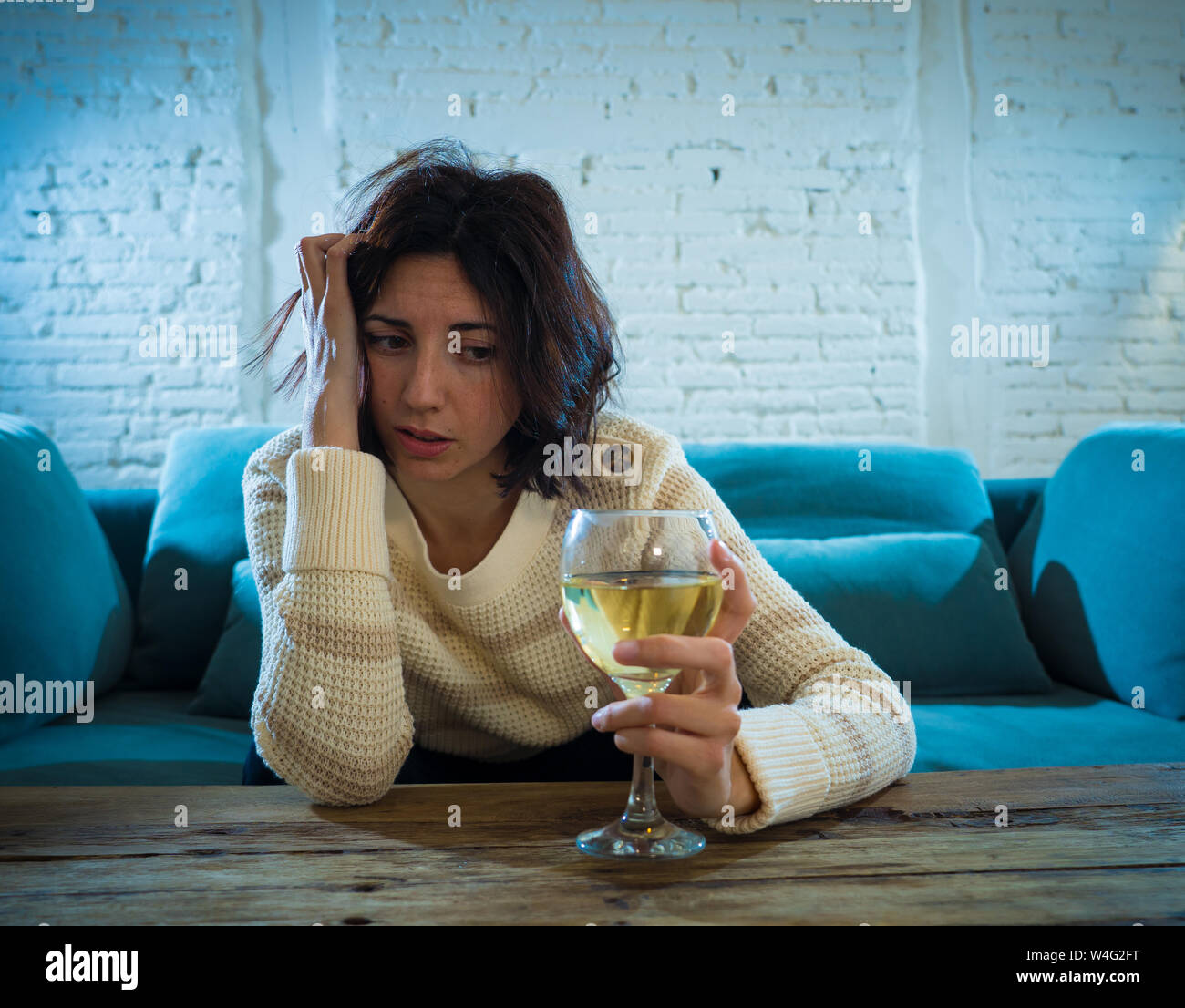 Stressed and hopeless young woman drinking a glass of wine alone at ...